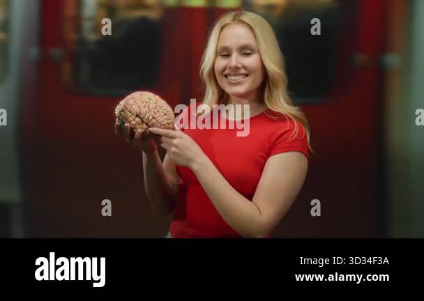 Woman holding a brain model at an underground station with a red shirt ...