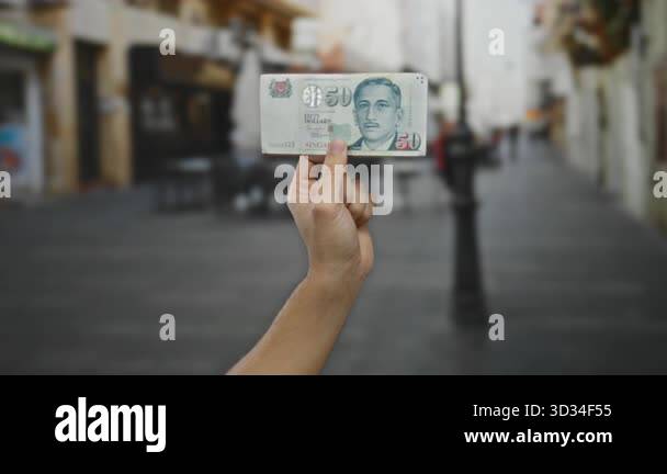 Caucasian man's hand holding singapore dollar in a city street ...