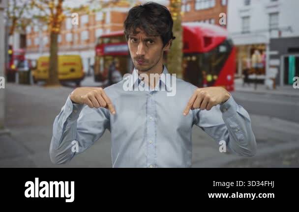 Man points both index fingers to light blue shirt on busy city street ...