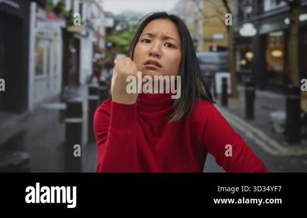 Woman in red sweater gestures on city street expressing determination ...