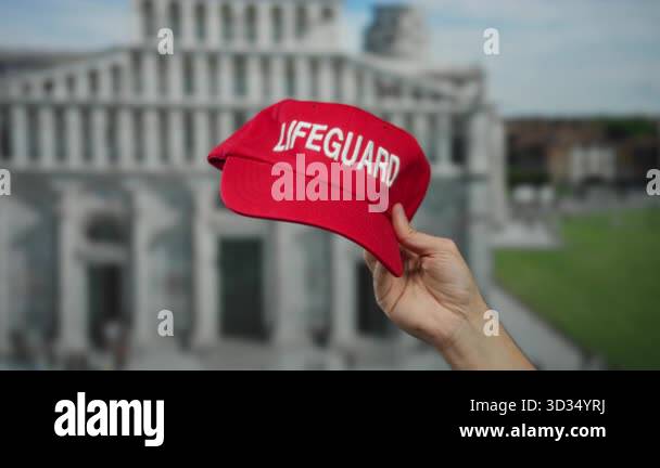 Man holding red lifeguard cap in front of leaning tower in pisa italy ...