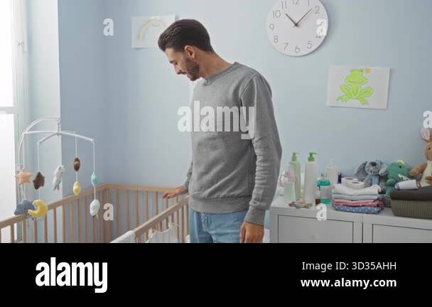 Young man stands in a cozy baby room with a cradle and baby essentials ...
