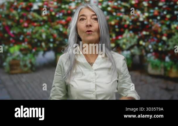 Senior woman on street gesturing ok in front of eye with colorful ...