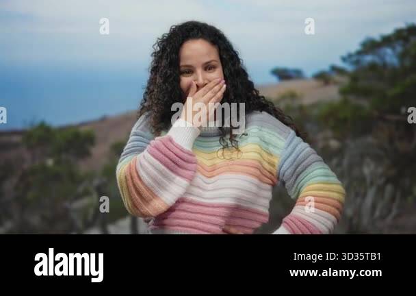 Woman smiling in colorful sweater standing on beach promenade with sea ...