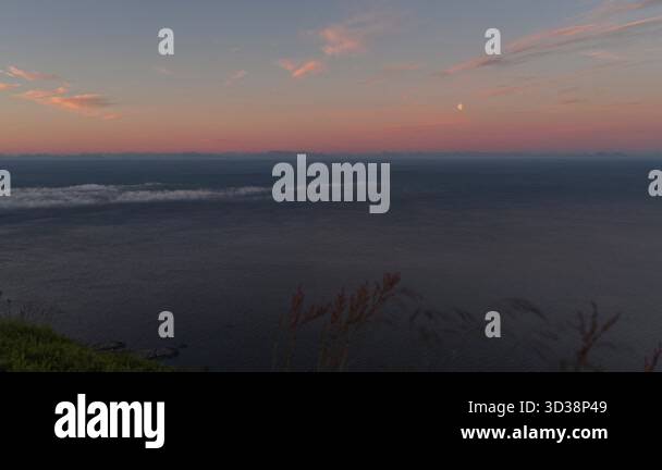 Pink and orange hues paint the sky as the sun sets over a tranquil ...