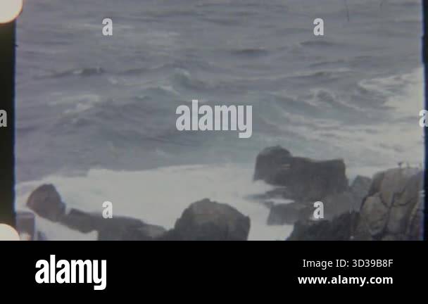 Waves crash against coastal rocks in the ocean, captured on 8mm film ...