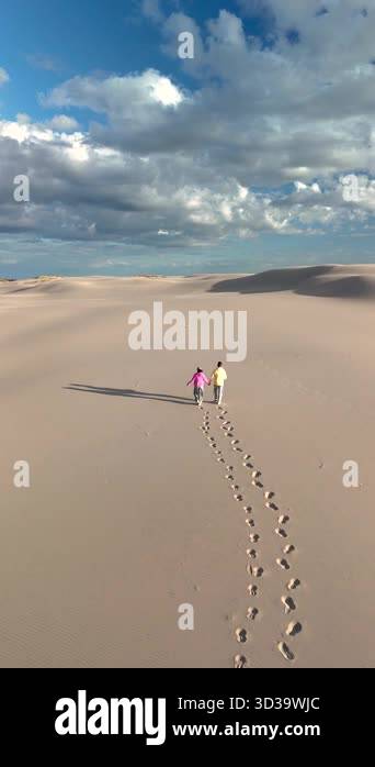 Two people wander through the vast sand dunes of Rabjerg Mile, Denmark ...