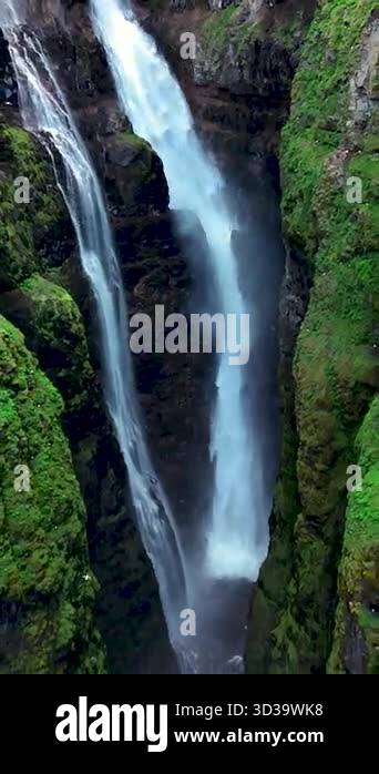 Glymur waterfall cascades dramatically down rugged cliffs surrounded by ...