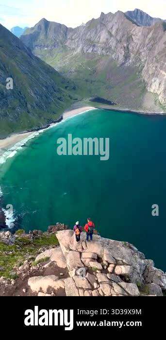 Hikers enjoy the stunning panoramic views from the Ryten Kvalvika Beach ...