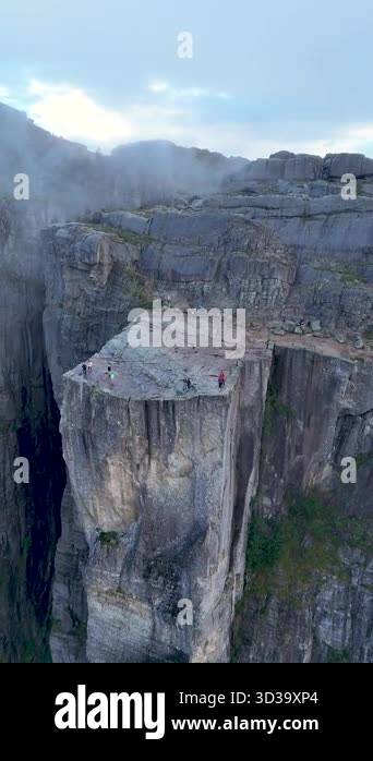 Explore the stunning cliffs of Preikestolen in Norway. Visitors gather ...