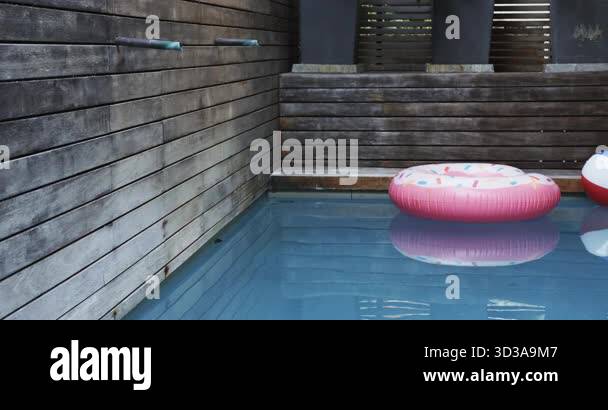 pink donut float floating in backyard pool, featuring beach ball, pool ...