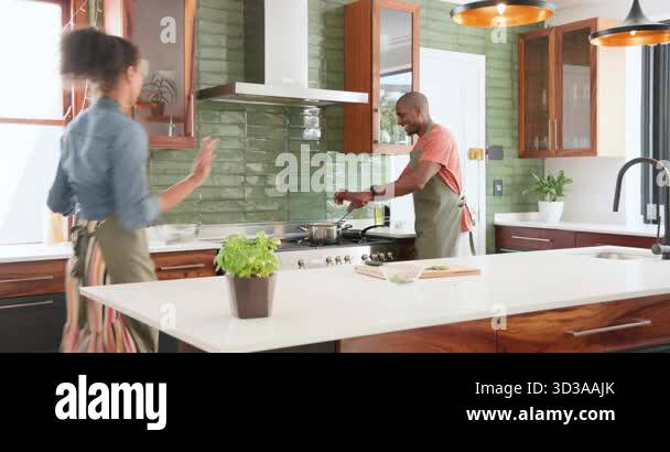 Diverse couple cooking together in modern kitchen, enjoying ...
