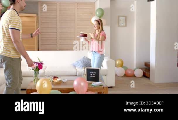 Celebrating new job, friends enjoying cake and balloons in living room ...