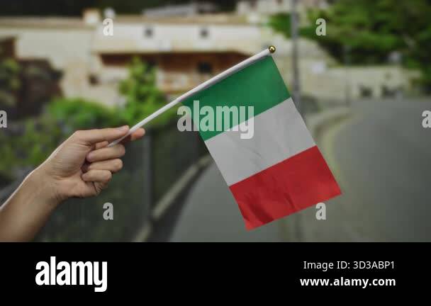 Hand waving italian flag outdoor in a picturesque city street ...