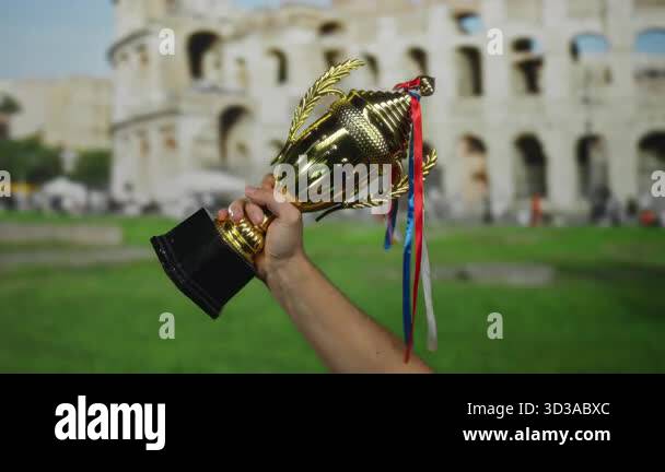 Man raising a golden trophy outdoors in front of the iconic roman ...