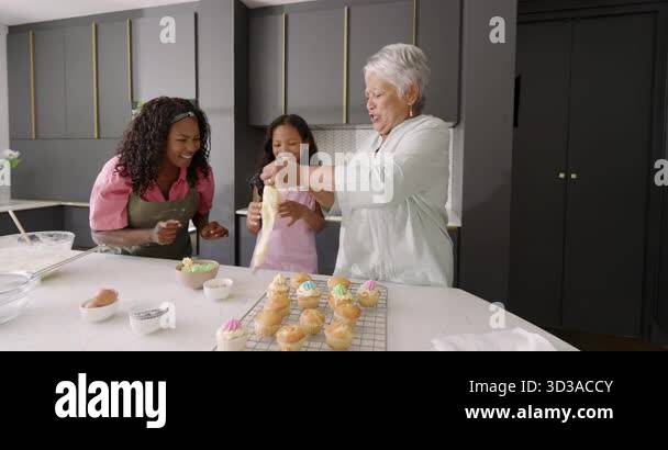 Three generations baking cupcakes together in modern kitchen, sharing ...