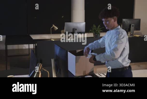 Young professional packing office items into box, preparing for career ...