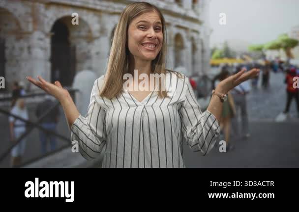 Young woman smiling with open arms in front of ancient coliseum on ...