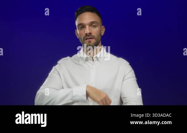 Tired young hispanic man in a white shirt poses thoughtfully against a solid blue background ...