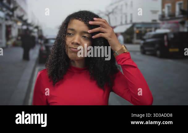 Woman touching forehead with hand while standing on busy city street ...