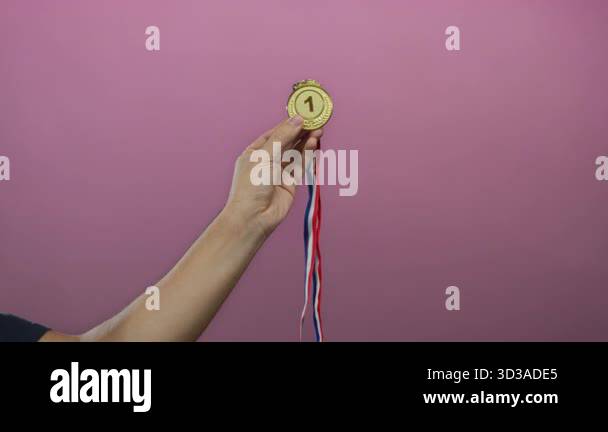 Man holding gold medal with blue and red ribbon against a pink ...