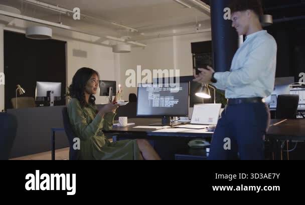 Diverse colleagues collaborating on computer code in modern office during night shift ...