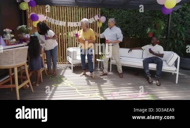 Diverse family enjoying outdoor birthday party, smiling and playing ...