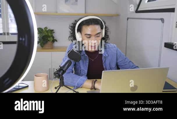 Ring light turning on prompts non-binary creator leaning into microphone, typing on PC at home ...