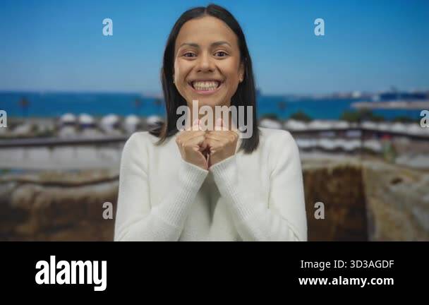 Woman celebrating feeling ecstatic with hands on face outdoors against ...