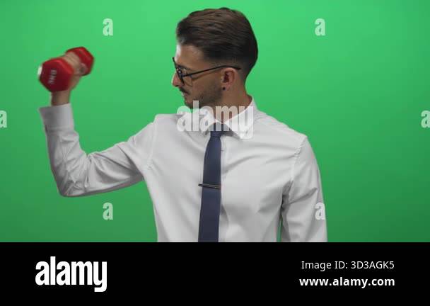 Man in white shirt and tie lifts red dumbbell with flexed arm in studio ...