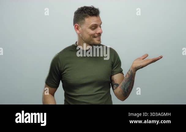 Young hispanic man with tattoos pointing to his open palm against a ...