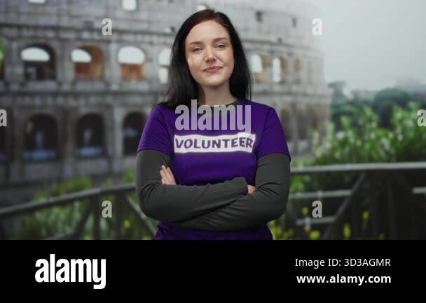 Woman with brunette hair and purple volunteer shirt stands confidently ...