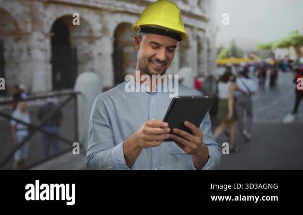 Young hispanic man in a hardhat using a tablet outside the roman ...