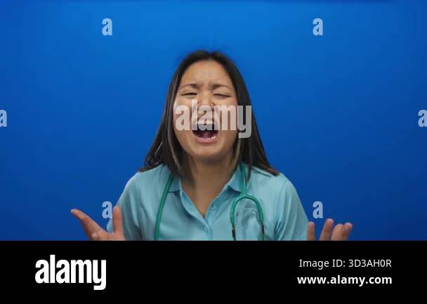 Young chinese woman doctor in distress with stethoscope over blue ...