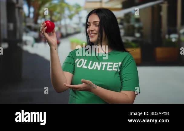Woman smiling outside in city setting wearing green volunteer shirt ...