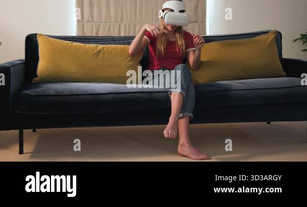 Teen girl using VR headset on couch, enjoying immersive virtual reality ...