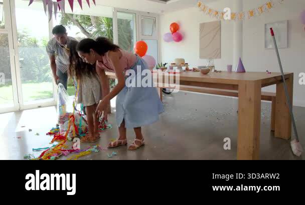 Diverse family cleaning up colorful confetti at birthday party room ...