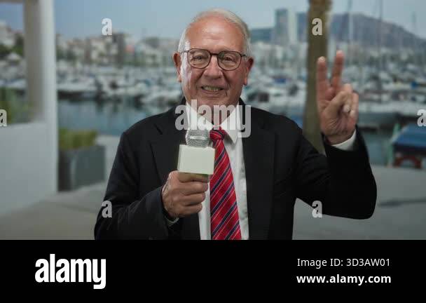 Senior man with microphone reporting outdoors at a seaside port with ...