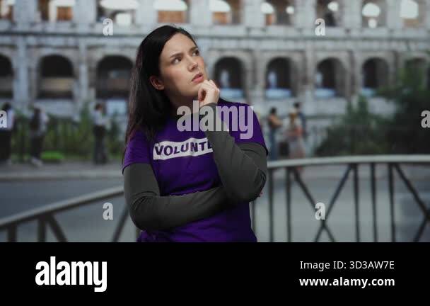 Woman volunteer with brunette hair stands thoughtfully at the coliseum ...