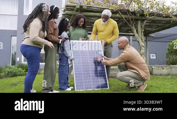 Diverse family and technician positioning solar panel in backyard ...