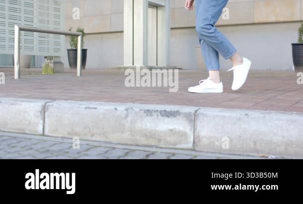 At start woman walking along brick sidewalk at building entrance toward ...