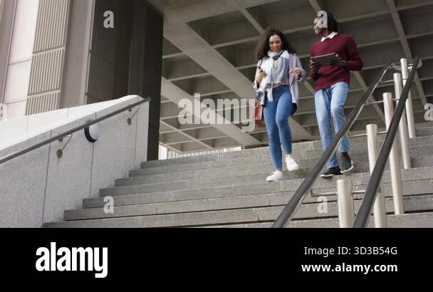 Stepping off top step, Coworkers descending entry stairs discussing ...