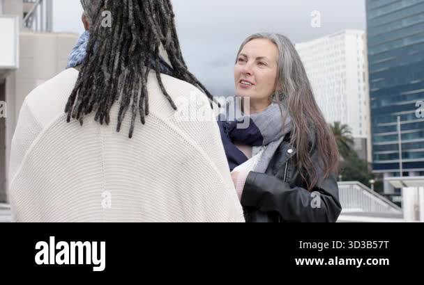 Diverse female friends conversing and nodding on urban balcony after ...