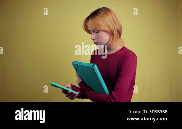 Young female student holding a folder while scrolling on her smartphone ...