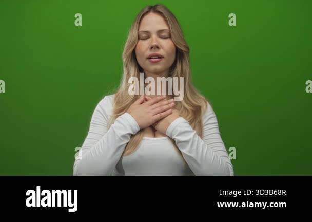 Woman places palms on chest with closed eyes in green portrait studio ...