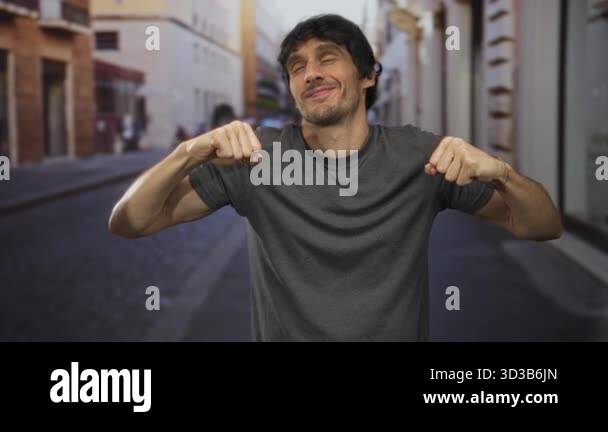 Young man in grey shirt leans forward with clenched fists and tense ...