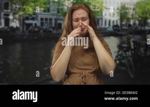 Woman pinched nose on street canal beside waterway and leaning against ...