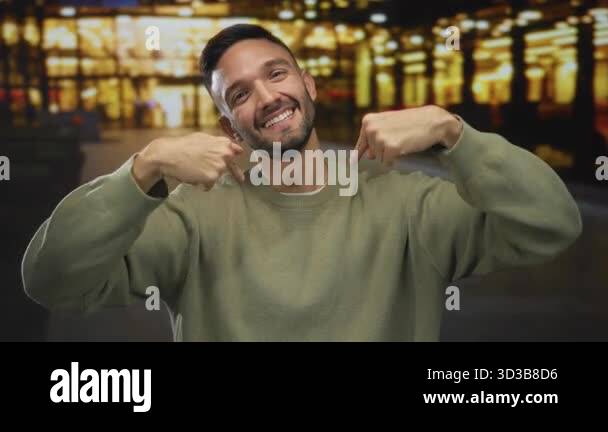 Young man pointing at himself and smiling on an urban city street with ...