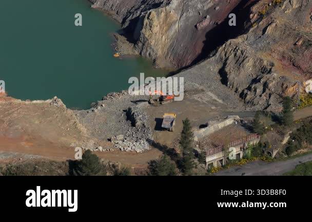 Aerial view of a quarry operation, featuring an excavator loading rocks ...