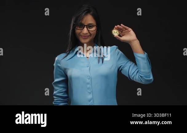Woman smiling holding monero coin against black backdrop symbolizing ...